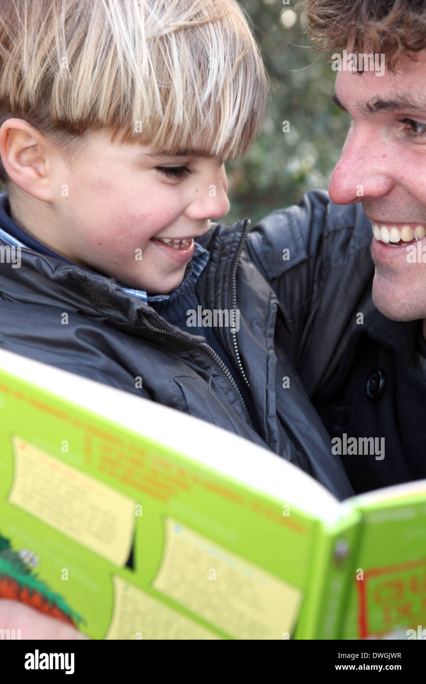 Man with little boy reading book outdoors Stock Photo - Alamy