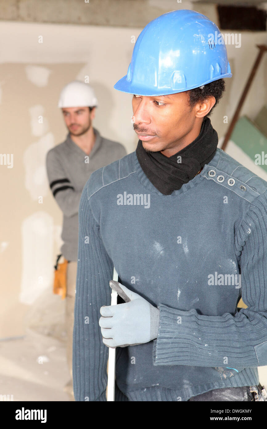 Two men carrying plaster board Stock Photo - Alamy