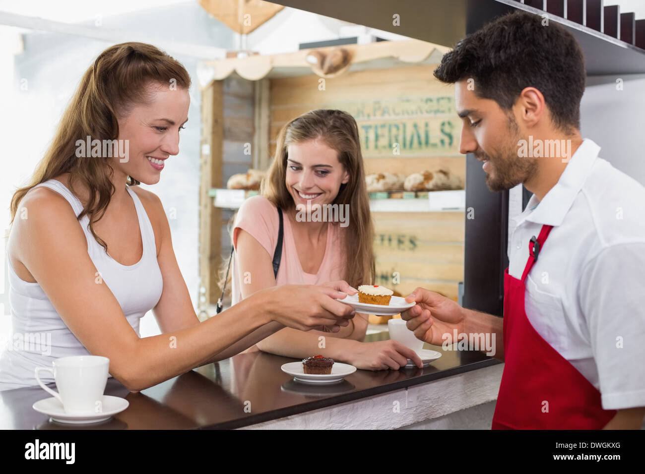Barista giving pastry to woman at counter in coffee shop Stock Photo ...