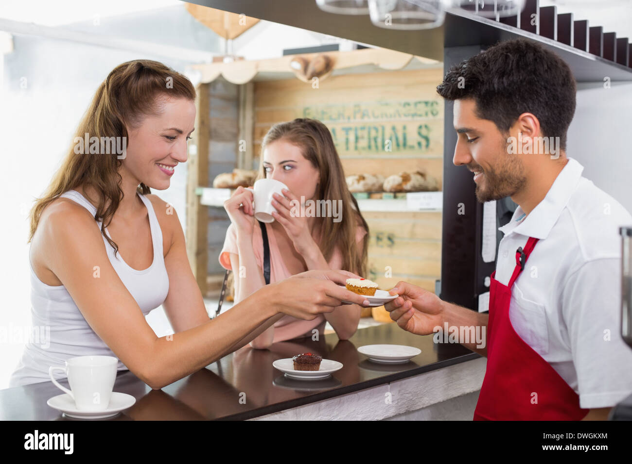 Barista giving pastry to woman at counter in coffee shop Stock Photo ...