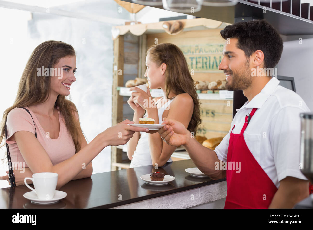 Barista giving pastry to woman at counter in coffee shop Stock Photo ...