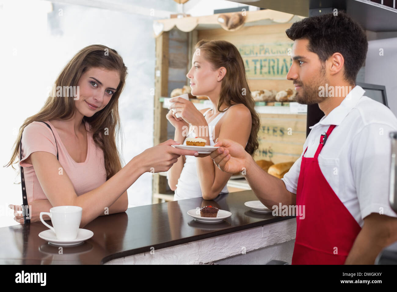 Barista giving pastry to woman at counter in coffee shop Stock Photo ...