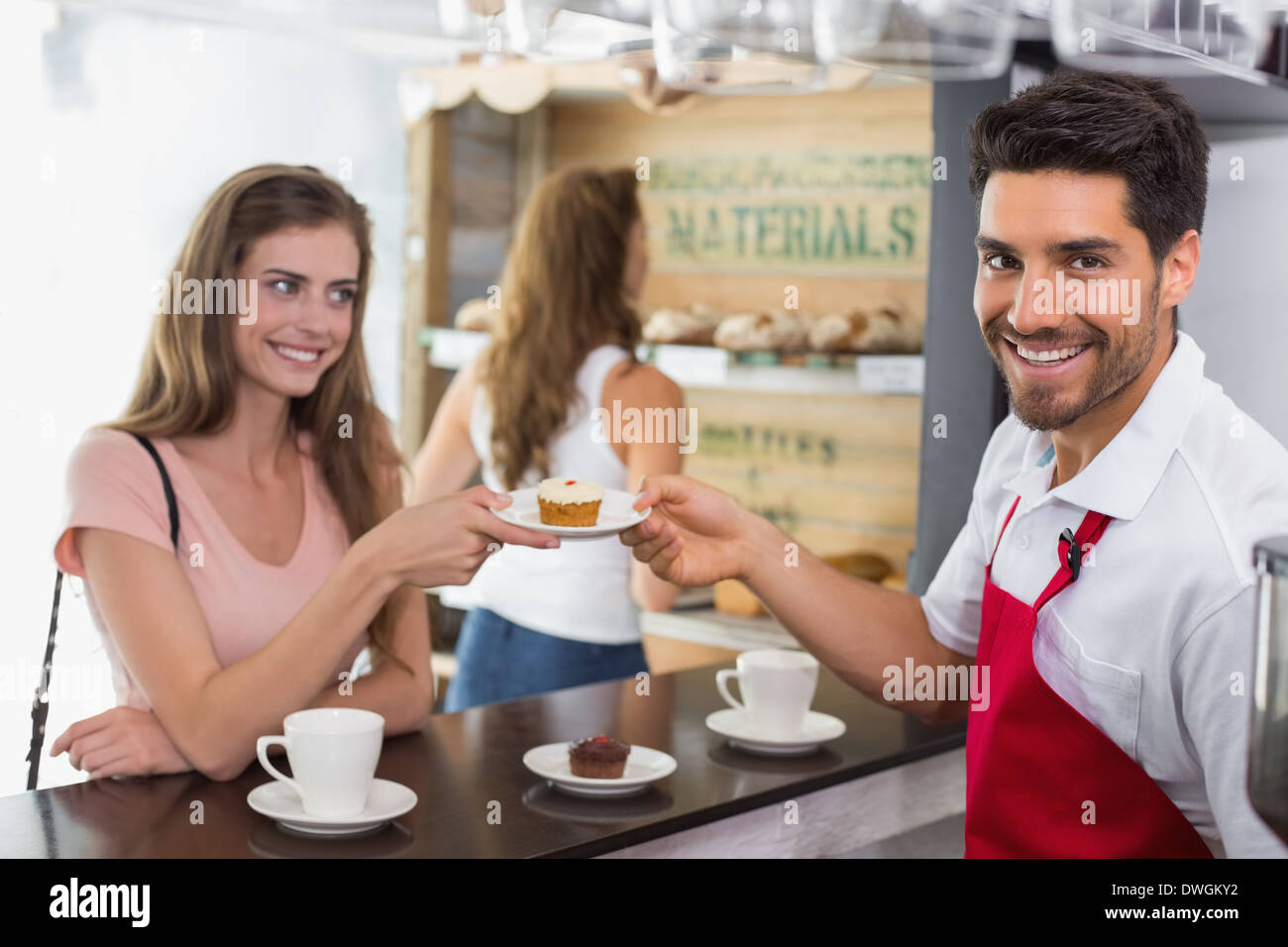Barista giving pastry to woman at counter in coffee shop Stock Photo ...