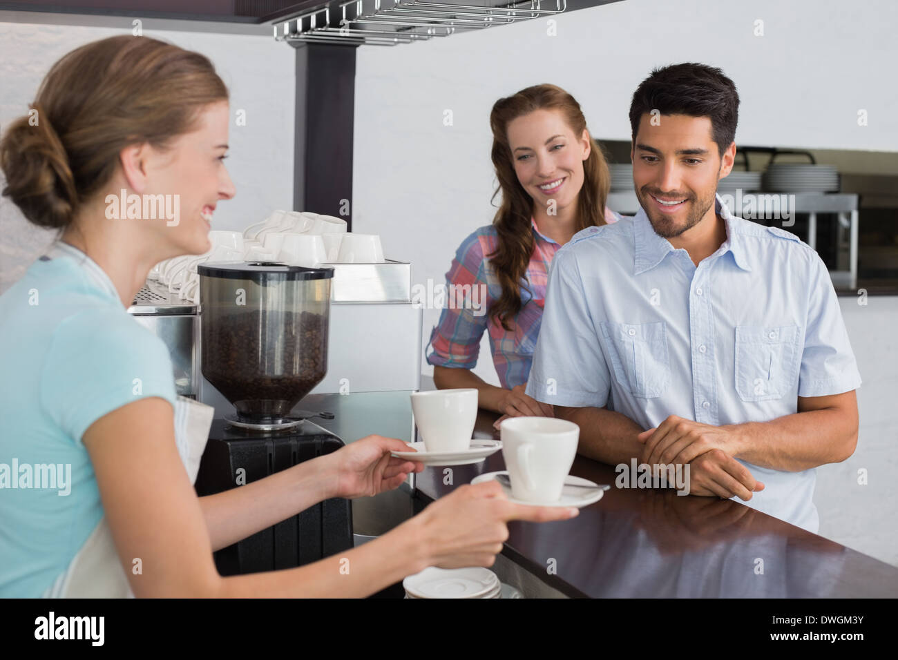 Smiling waitress giving coffee to a couple at coffee shop Stock Photo ...