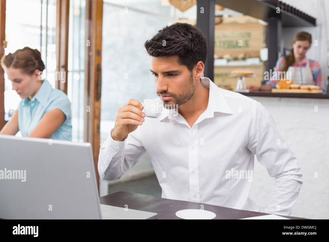 Man drinking coffee while using laptop in coffee shop Stock Photo - Alamy