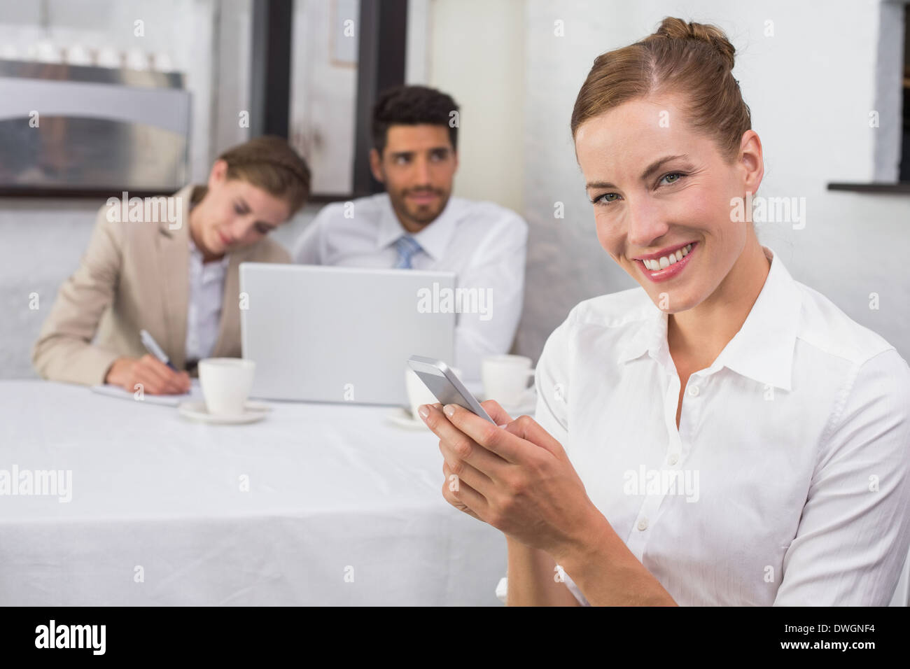 Businesswoman text messaging with colleagues at office desk Stock Photo ...