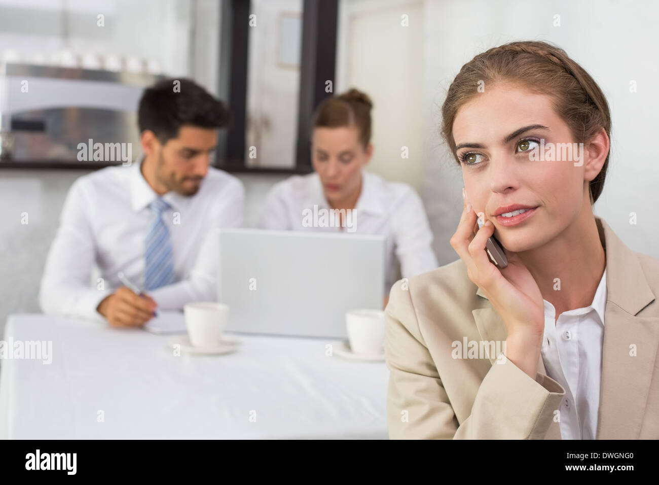 Businesswoman Using Mobile Phone With Colleagues At Office Desk Stock
