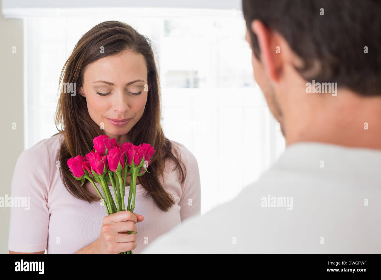 Beautiful young woman smelling flowers Stock Photo - Alamy