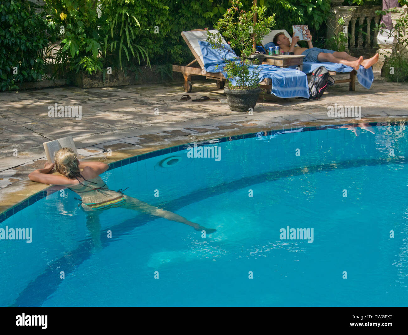 Woman reading in a swimming pool. Tourists in a luxury hotel in Bali ...