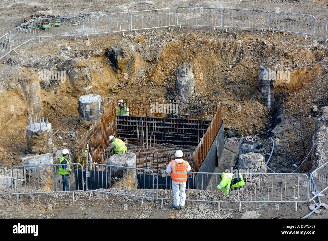 Steel fixers placing reinforcing rods in foundation cage around piles ...