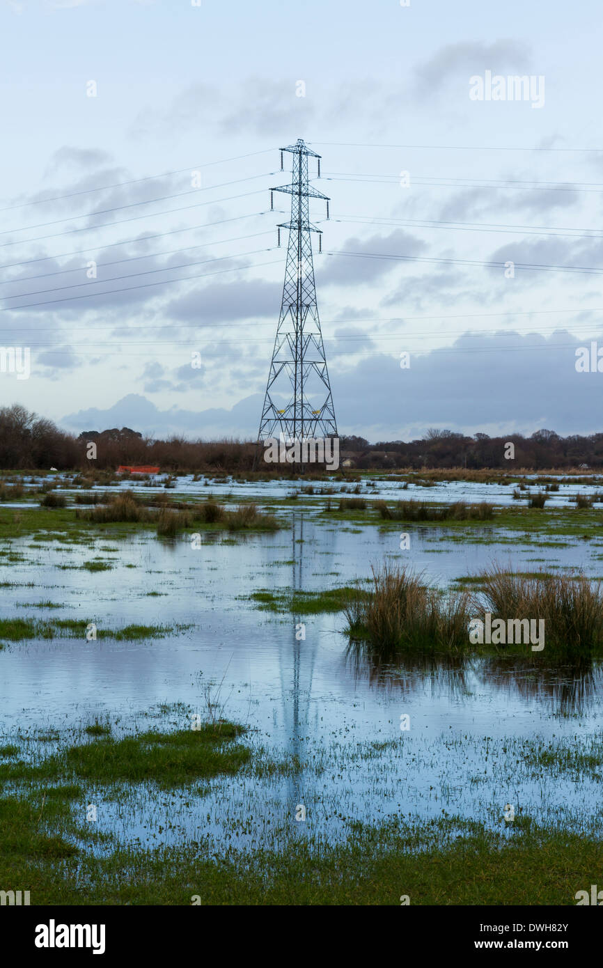 High voltage Pylon with its reflection in flooded Christchurch Meadows ...