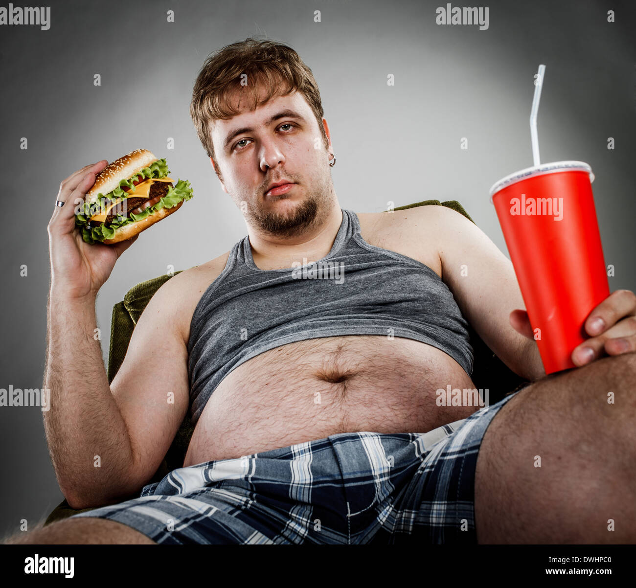 Fat man eating hamburger seated on armchair. Style fast food Stock ...