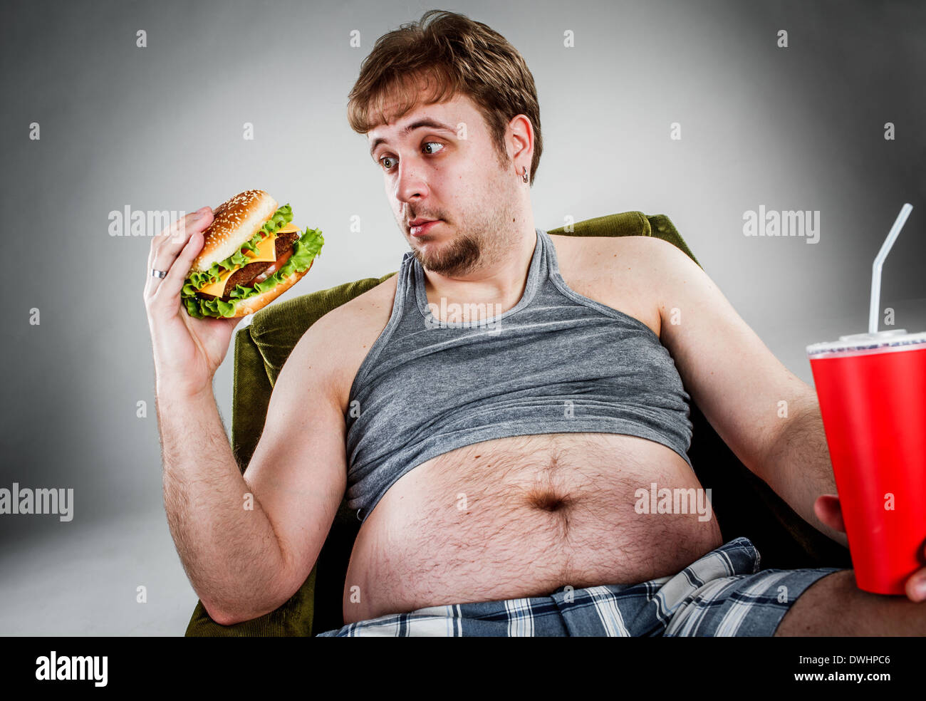 Fat man eating hamburger seated on armchair. Style fast food Stock ...