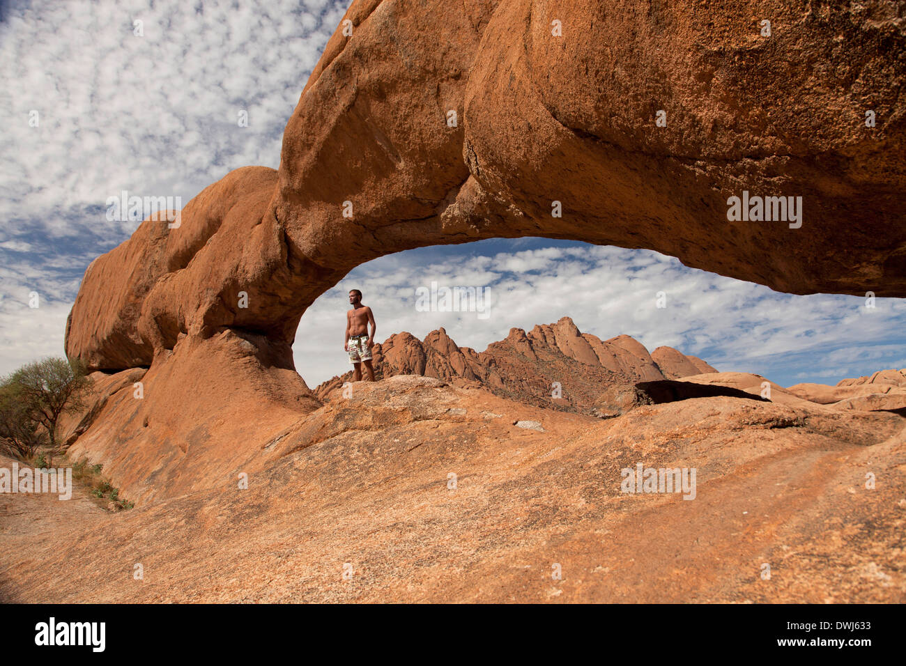tourist at the rock arch near the granite mountain Spitzkoppe, Namibia ...