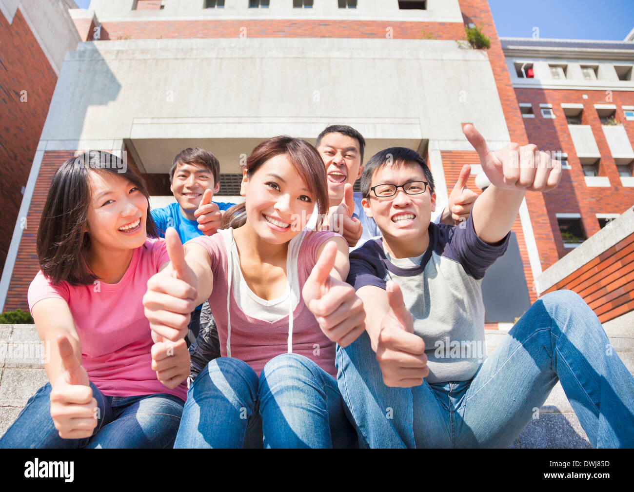 Happy students thumbs up together at campus Stock Photo - Alamy