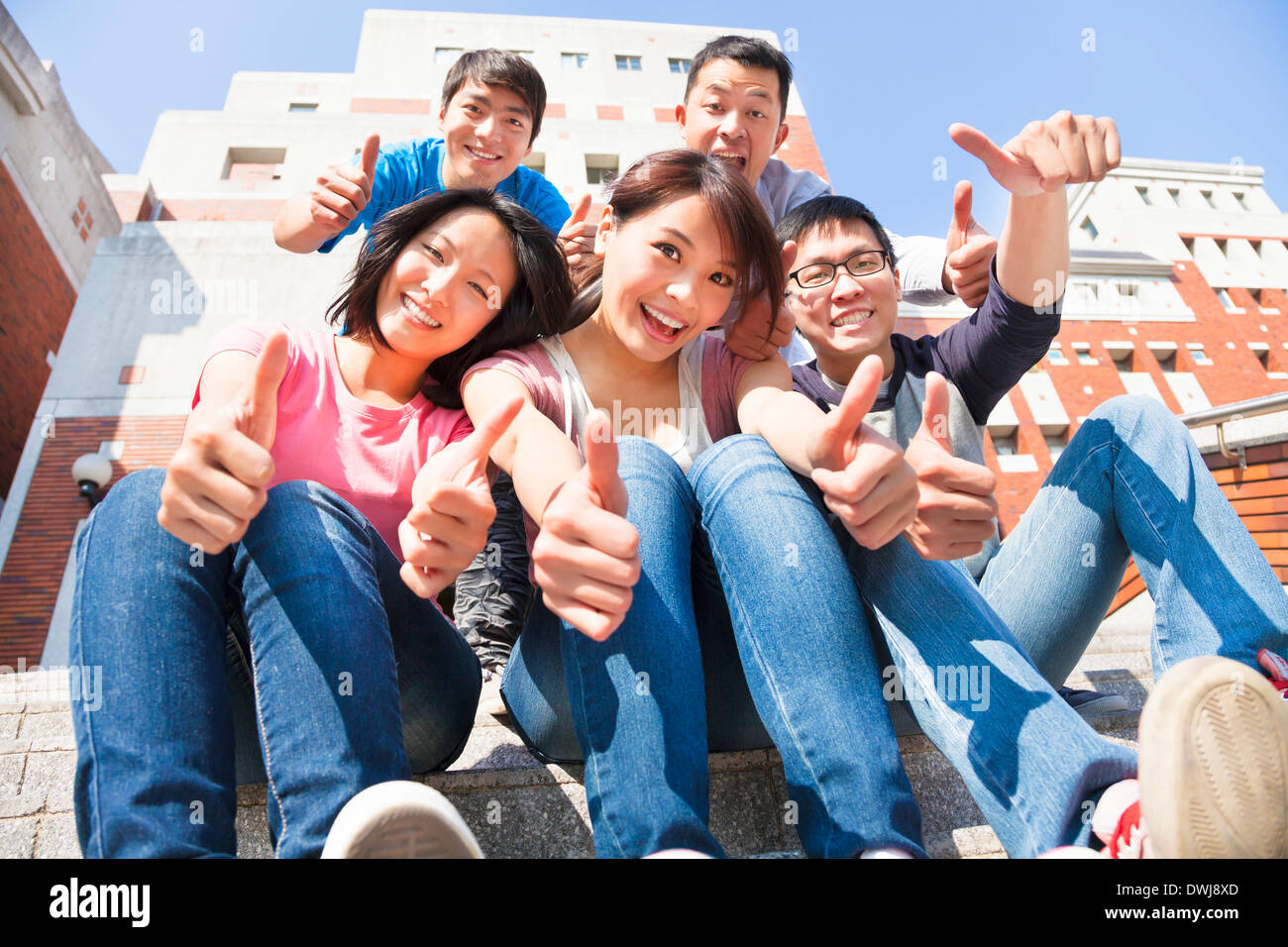 Happy and smiling students thumbs up together at campus Stock Photo - Alamy