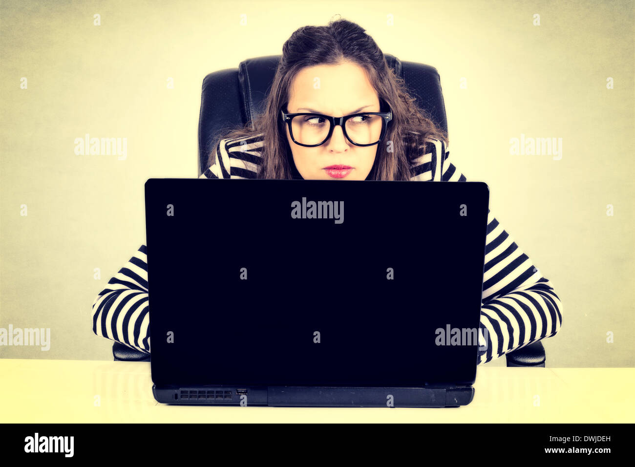 Suspicious businesswoman siting on the desk with laptop computer Stock ...