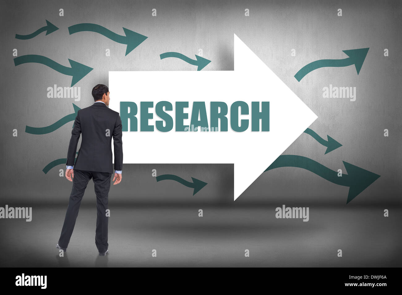 Businessman standing against white arrows on dark wall Stock Photo - Alamy