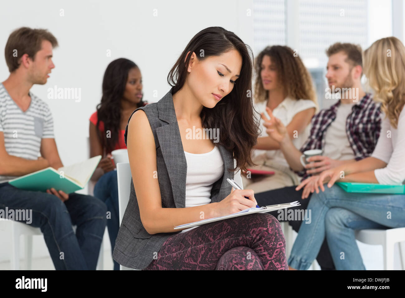 Woman taking notes while colleagues are talking behind her Stock Photo ...