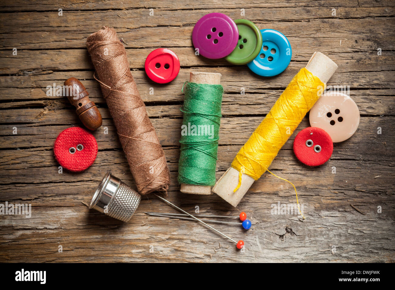 Set of colored sewing buttons and bobbin threads on wooden background ...