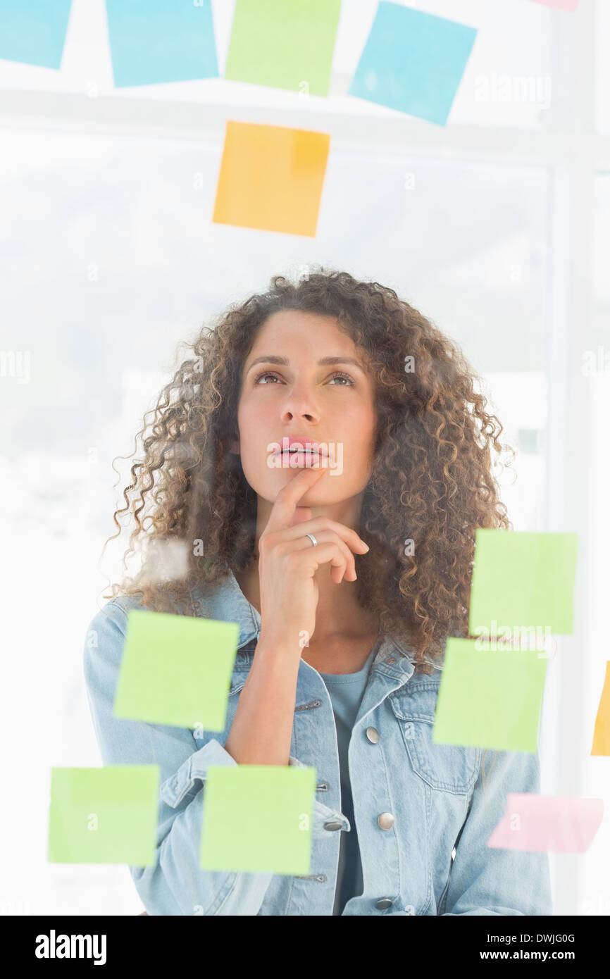 Thinking pretty designer looking at sticky notes on window Stock Photo ...