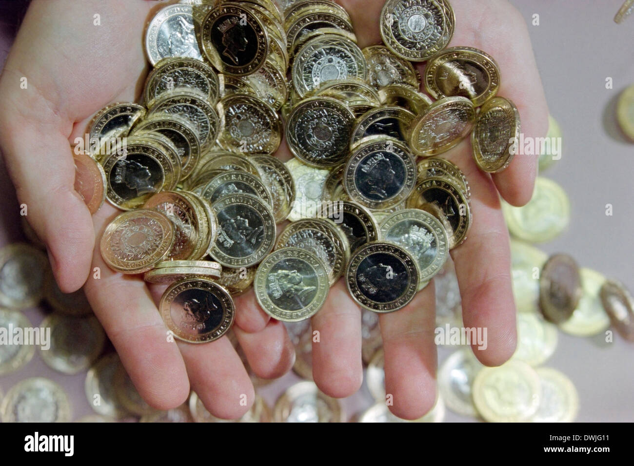 Close-up of a man holding a handful of £2 coins Stock Photo - Alamy