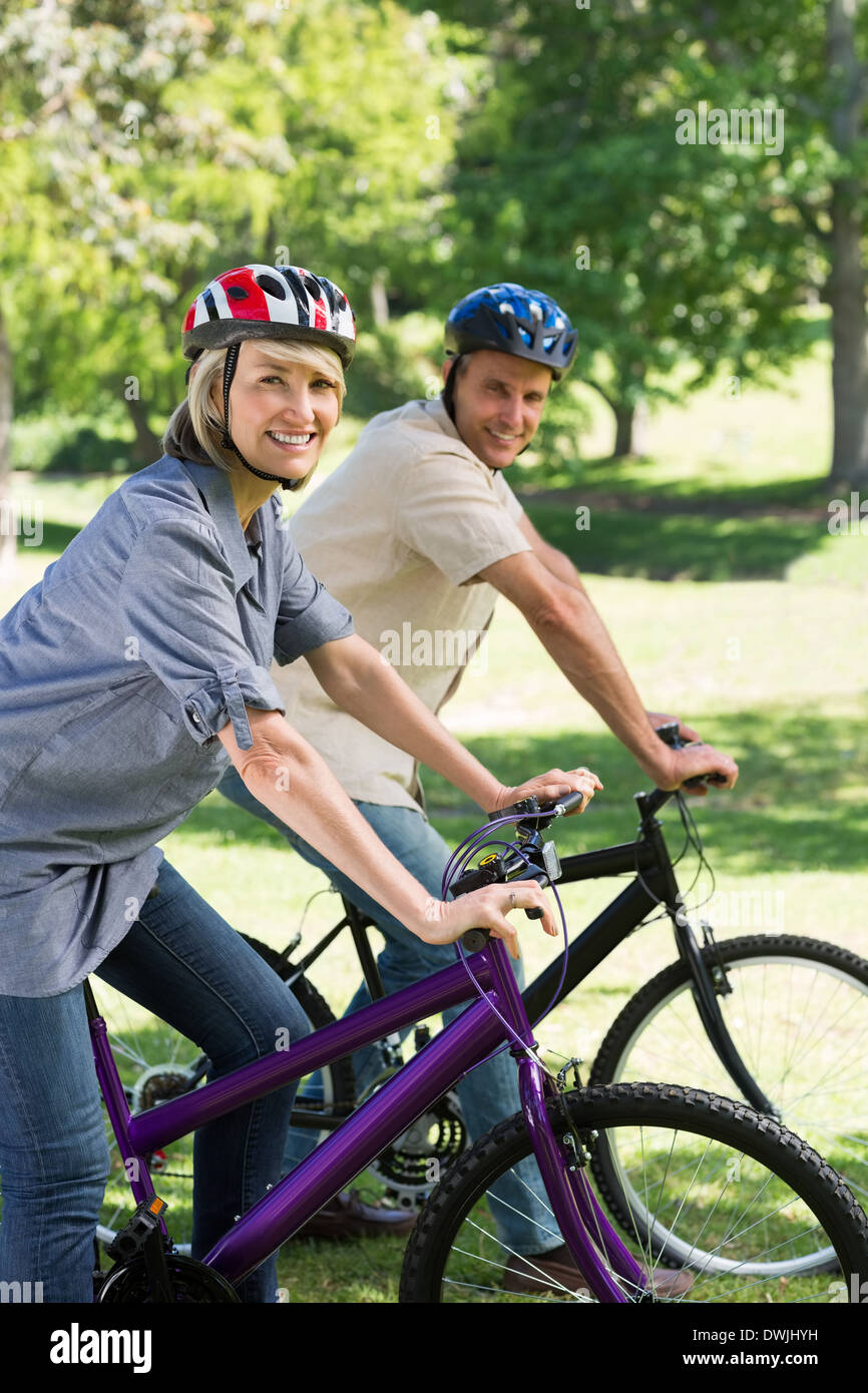 Happy couple cycling in park Stock Photo - Alamy