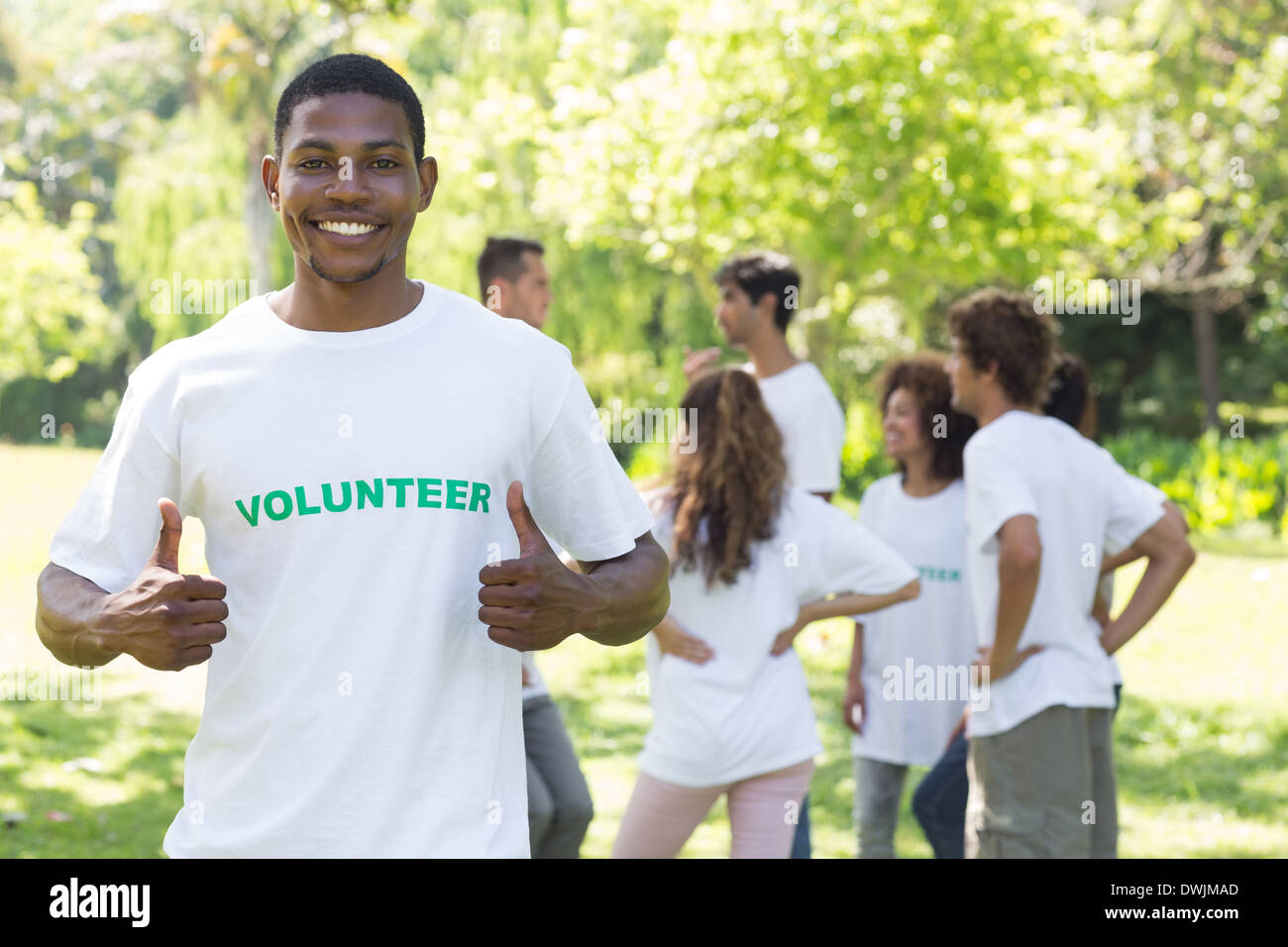 Smiling volunteer showing thumbs up Stock Photo - Alamy