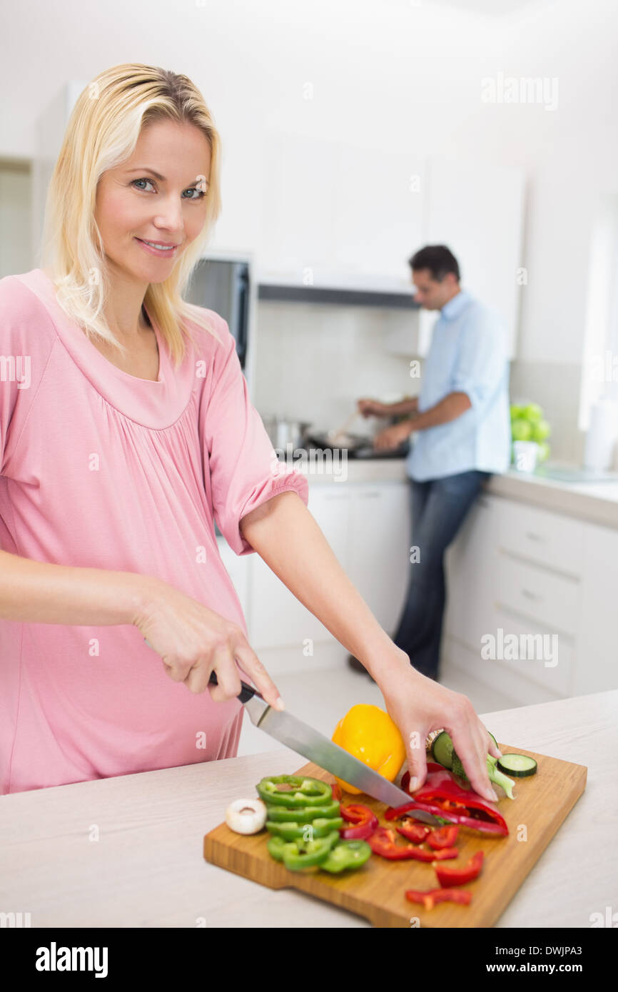 Woman chopping vegetables with man doing dishes at kitchen Stock Photo ...