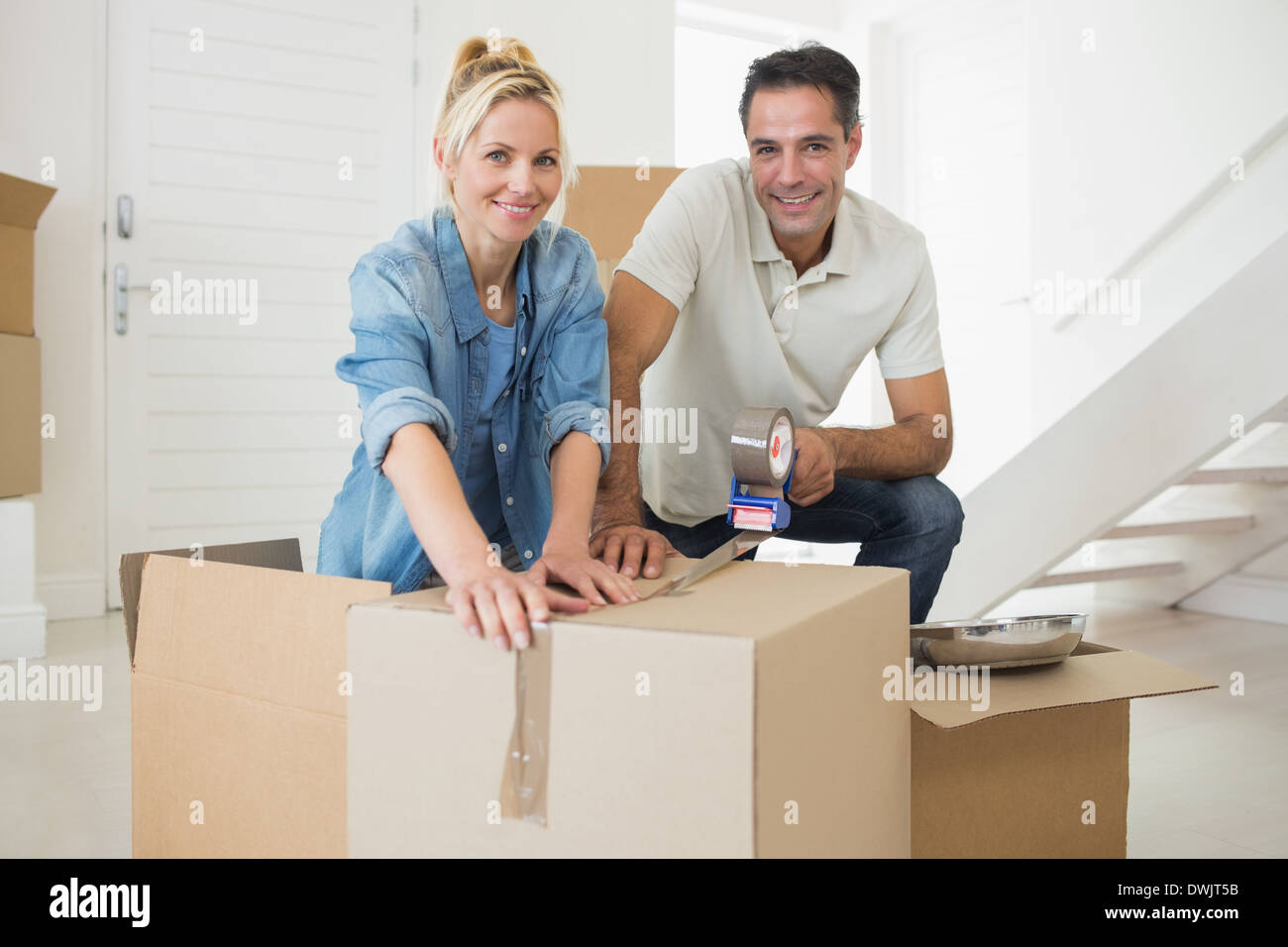 Smiling couple packing boxes in a new house Stock Photo - Alamy