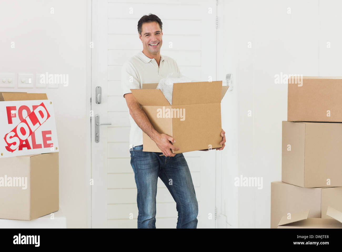 Smiling man carrying boxes in a new house Stock Photo - Alamy