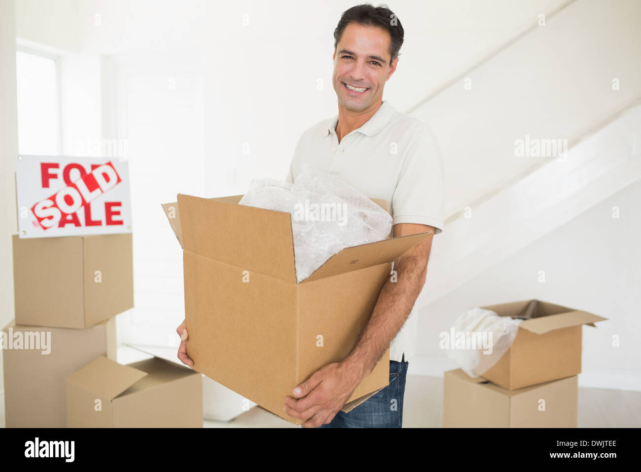 Smiling man carrying boxes in a new house Stock Photo - Alamy