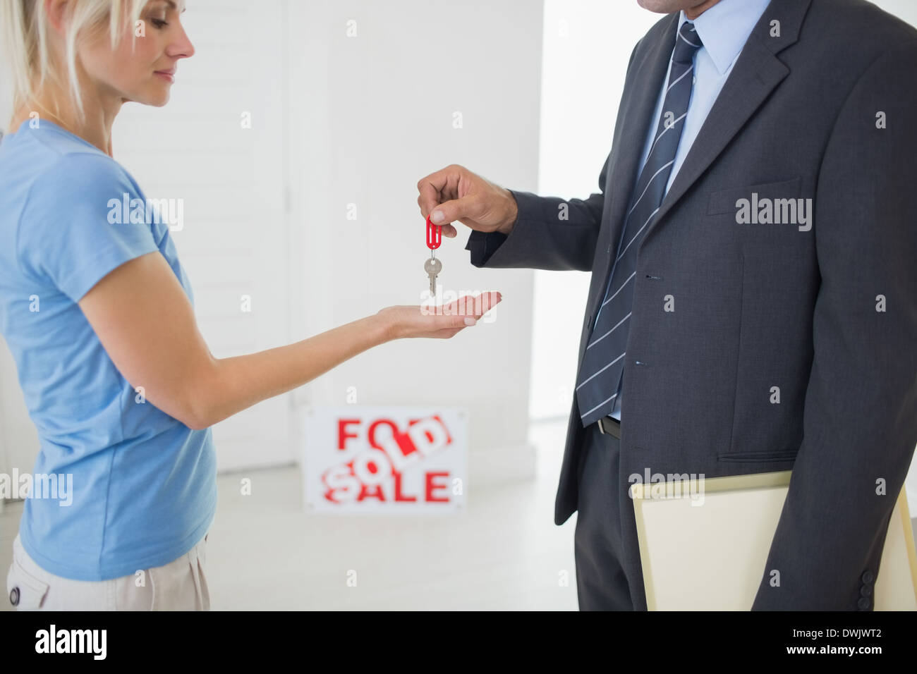 Real estate agent passing house key to woman Stock Photo - Alamy