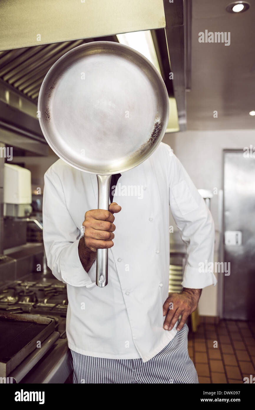 Cook holding pan in front of face in kitchen Stock Photo - Alamy