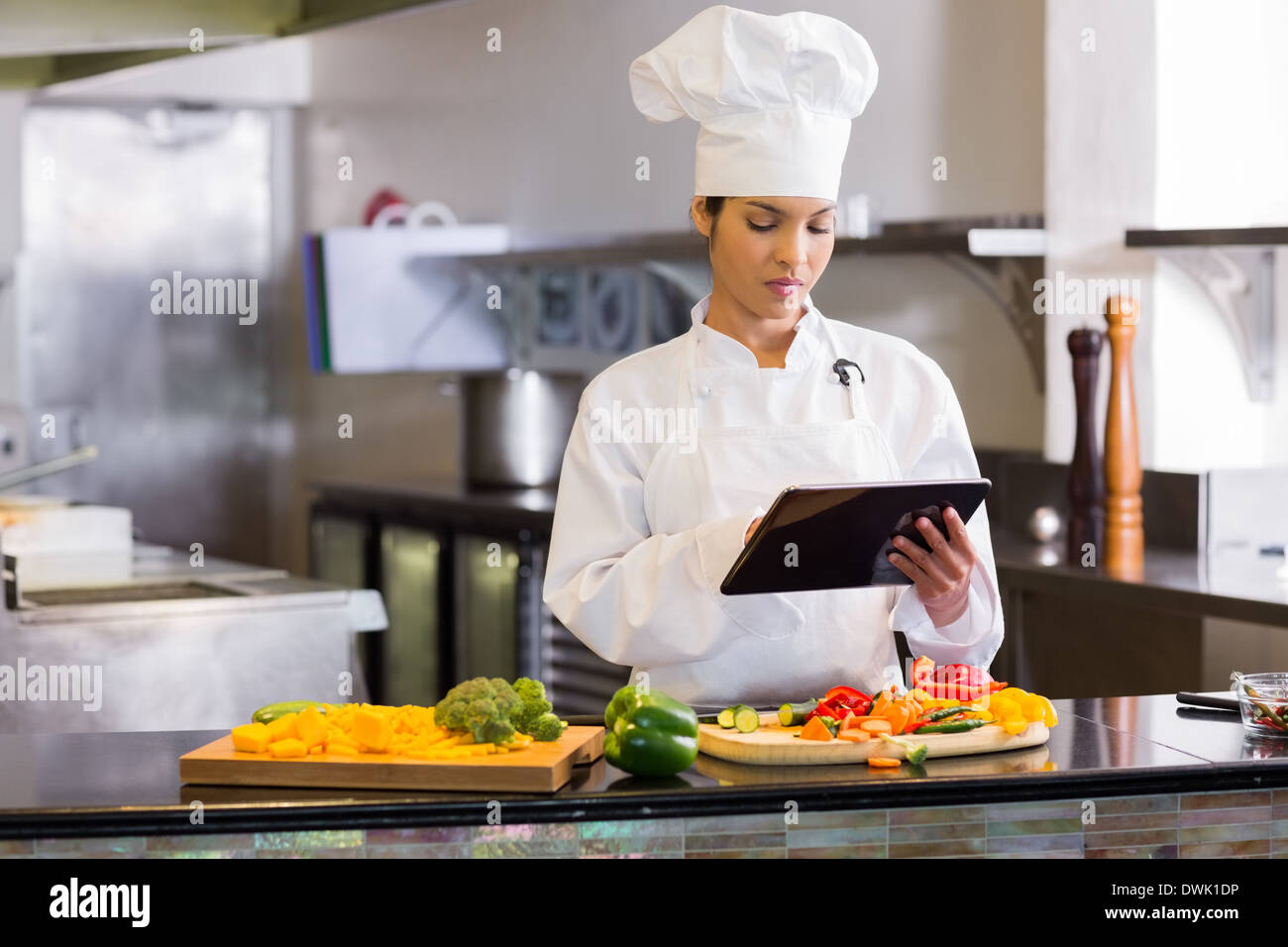 Female chef using digital tablet while cutting vegetables Stock Photo ...