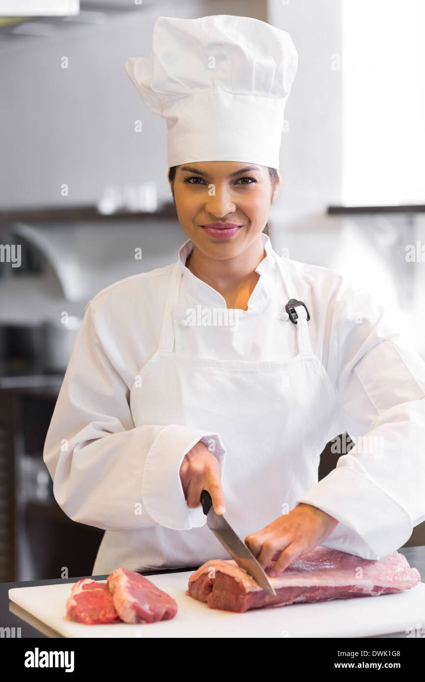 Smiling female chef cutting meat in kitchen Stock Photo - Alamy
