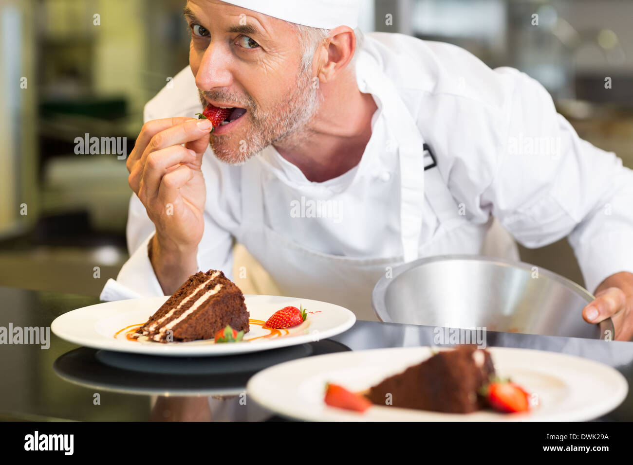 Smiling male pastry chef eating strawberry by dessert Stock Photo - Alamy