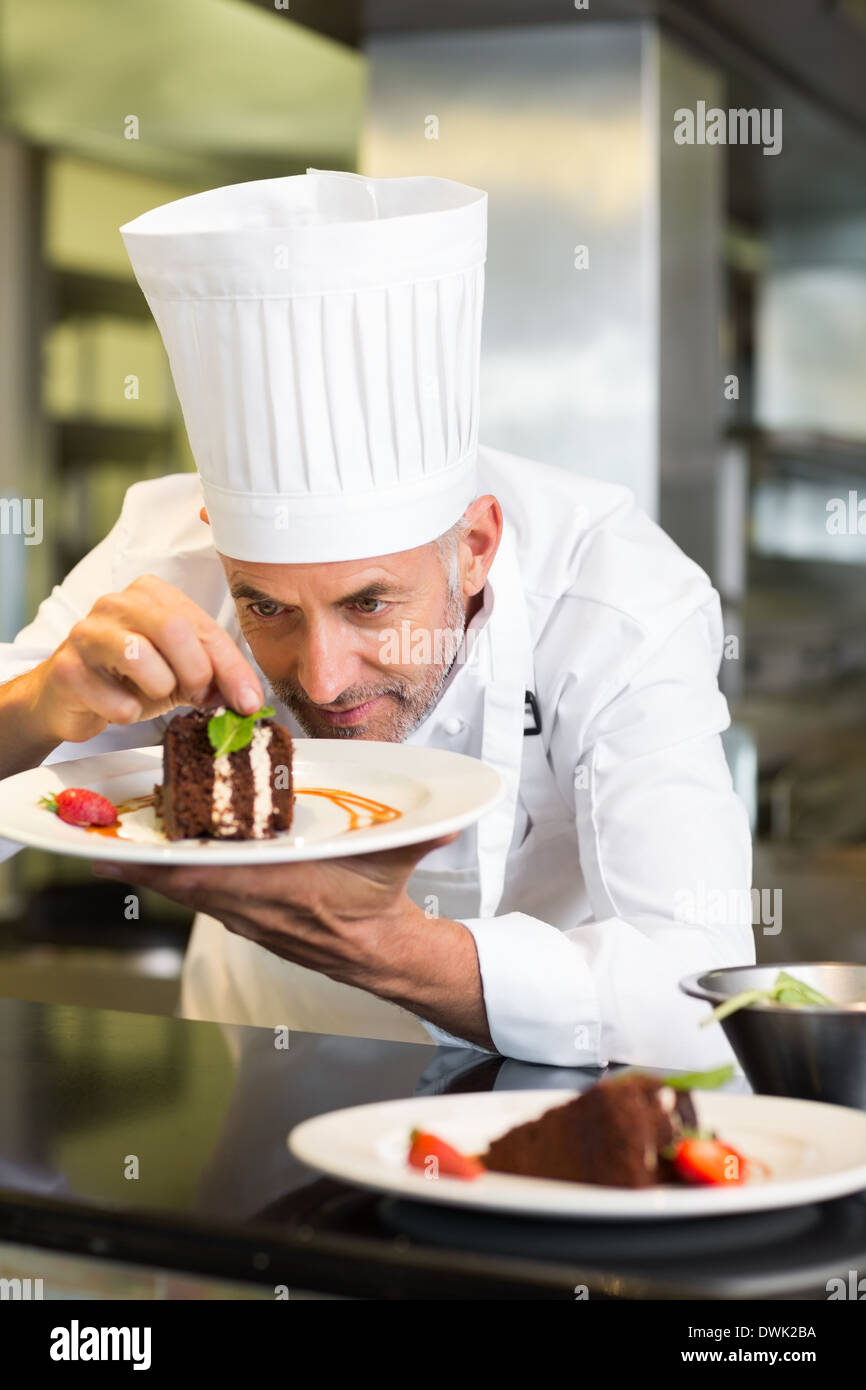 Concentrated male pastry chef decorating dessert in kitchen Stock Photo ...
