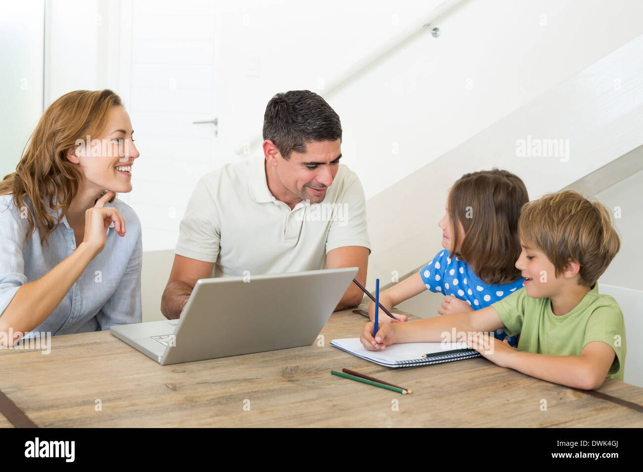 Parents with laptop assisting children coloring Stock Photo - Alamy