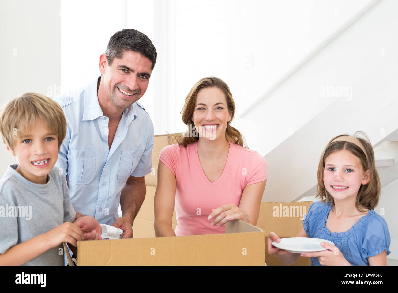 Happy family unpacking cardboard box in house Stock Photo - Alamy