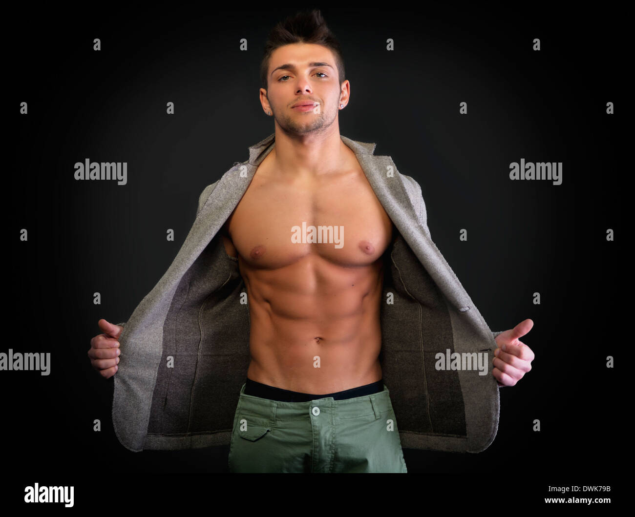 Confident, attractive young man with open jacket on muscular torso ...