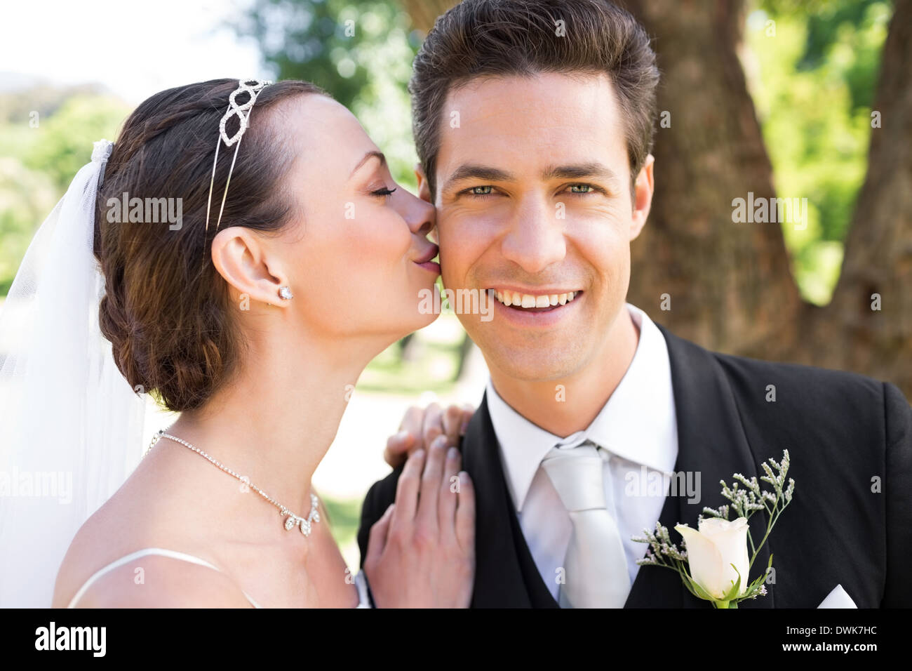 Bride kissing groom on cheek in garden Stock Photo - Alamy