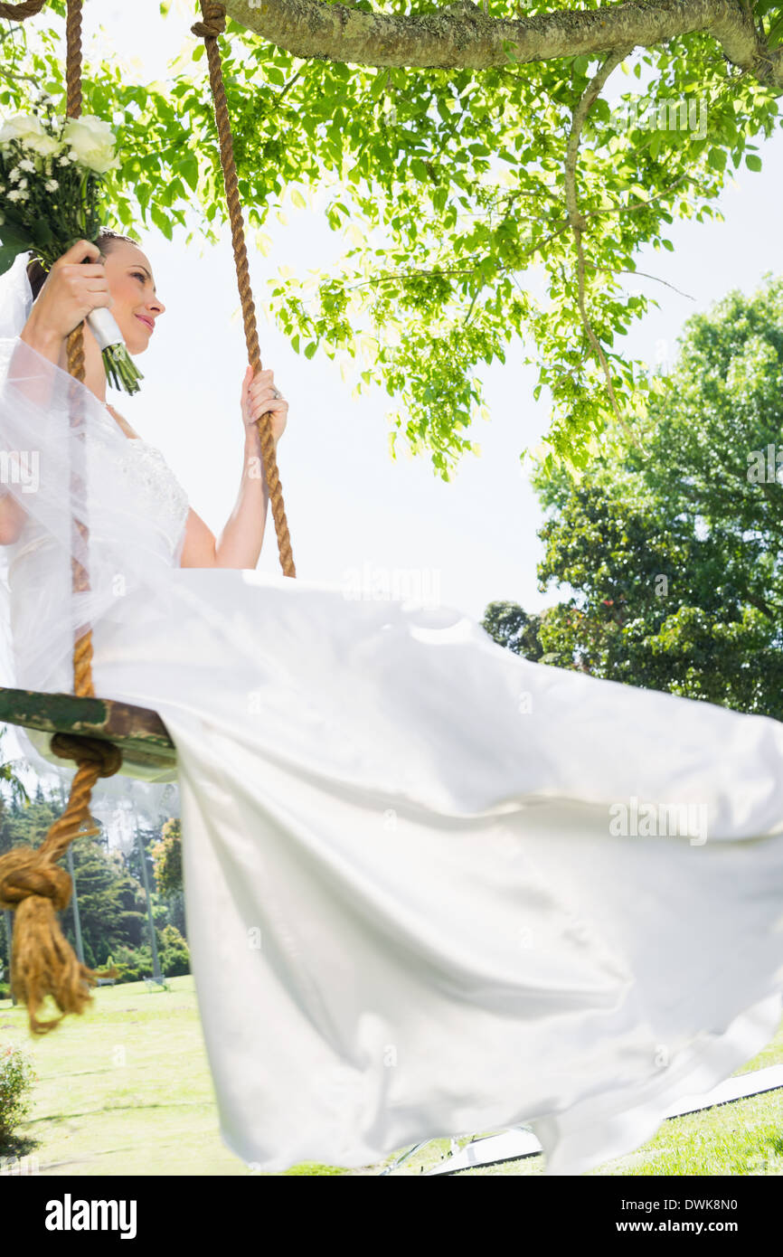 Thoughtful bride swinging in garden Stock Photo - Alamy