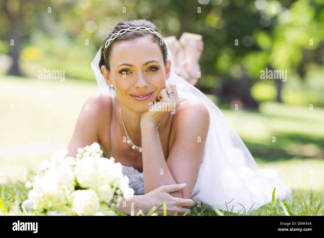 Young bride lying on grass in park Stock Photo - Alamy