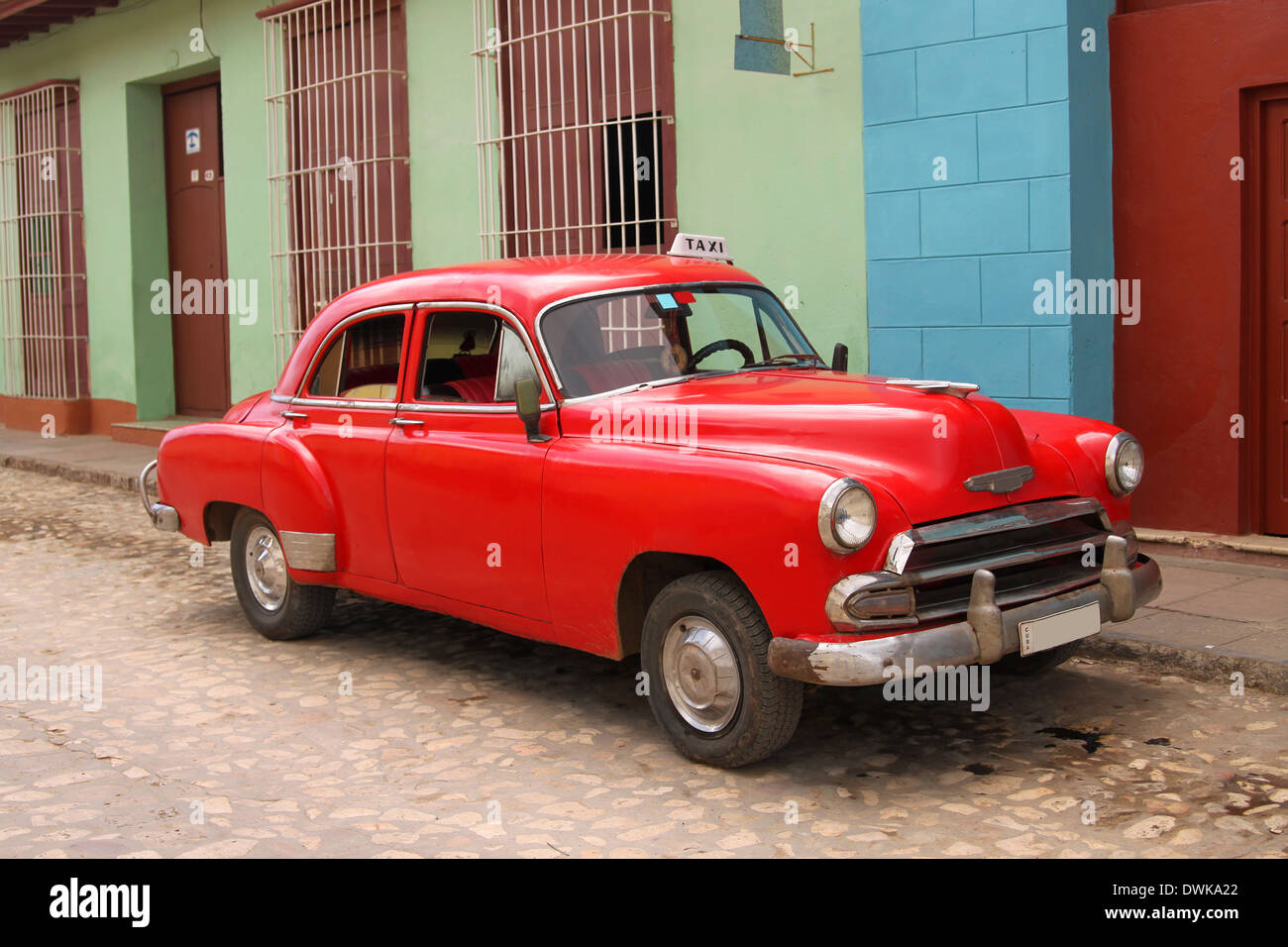 Bright red old fashioned, retro, taxi cab with colorful building ...