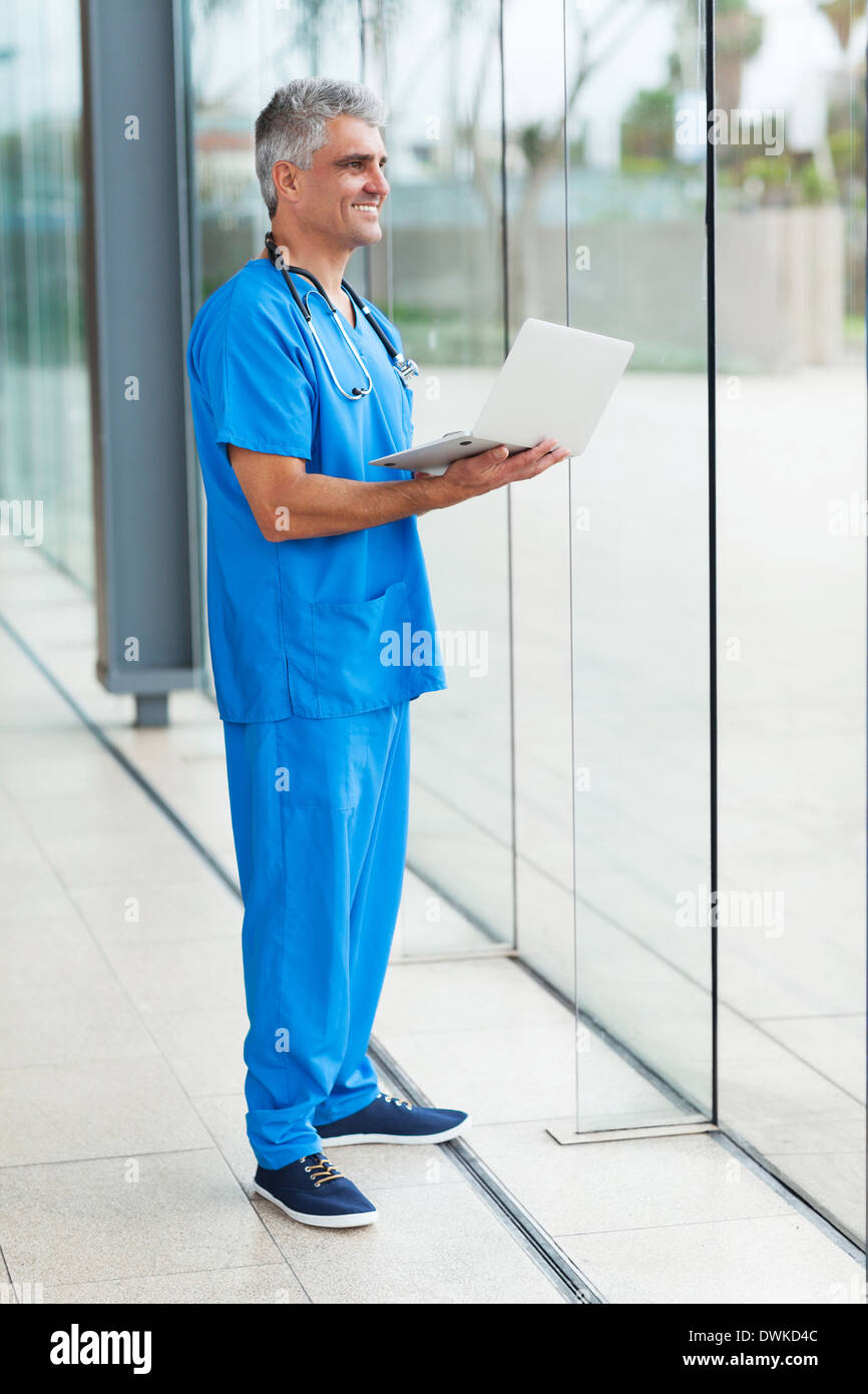 middle aged healthcare worker holding laptop computer at hospital Stock ...
