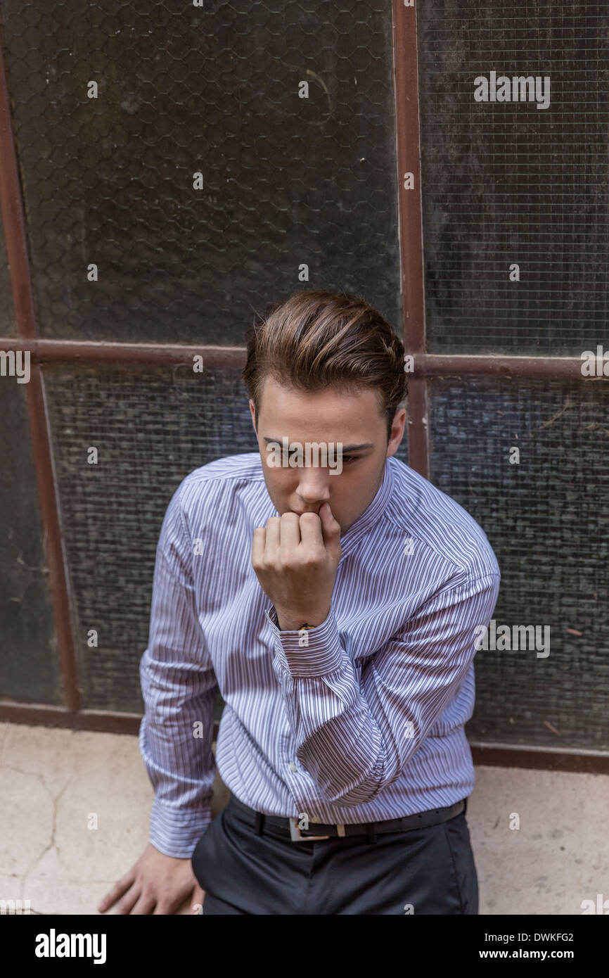 Handsome young caucasian male leaning against an industrial window ...