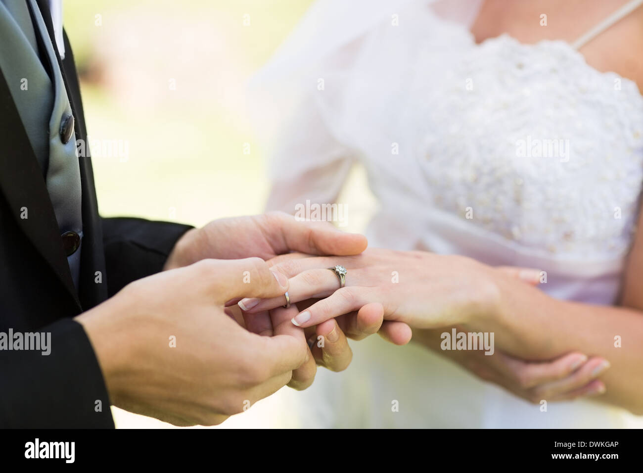 Groom placing ring on brides finger Stock Photo - Alamy