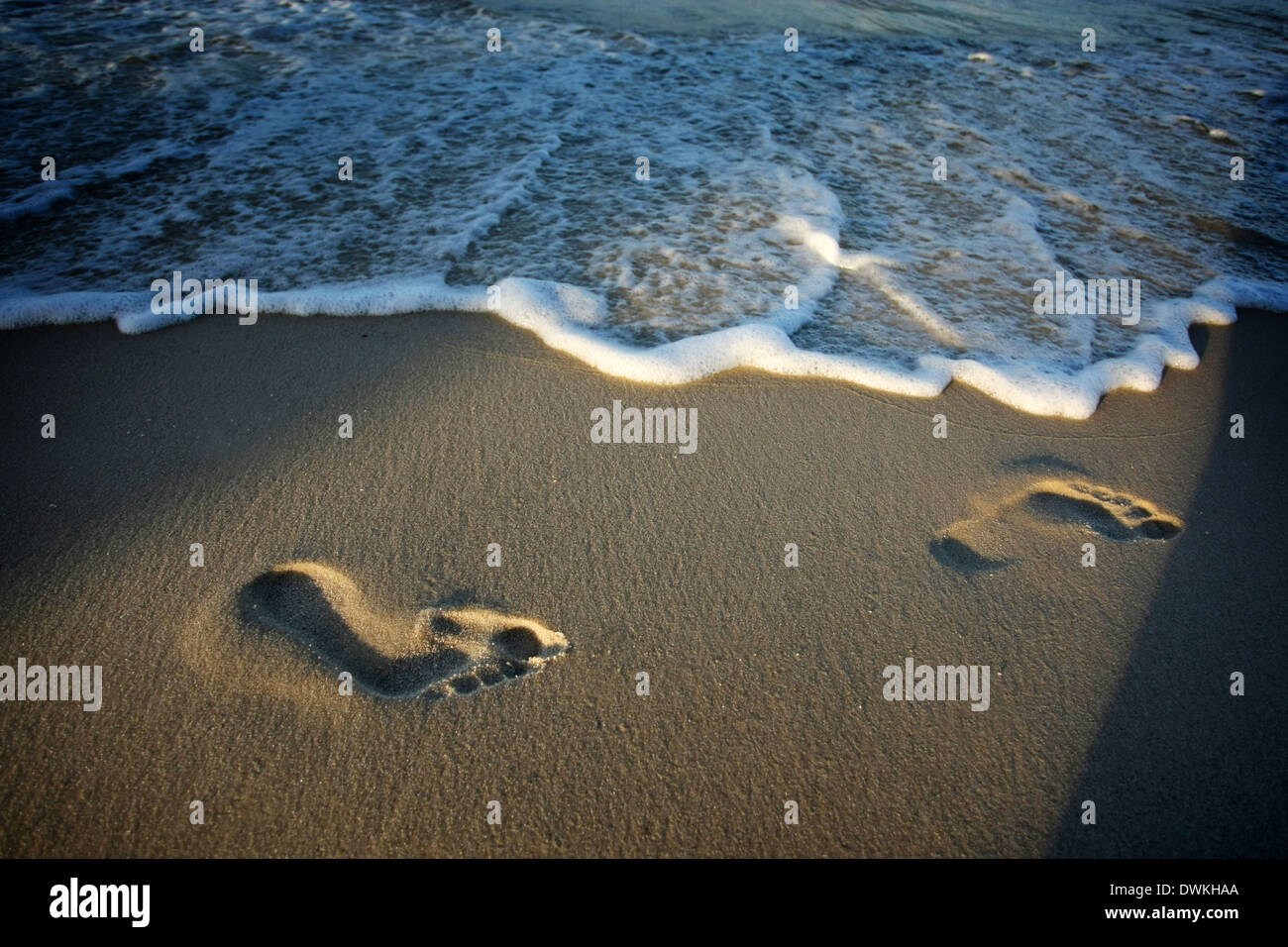 Footprints in the sand on the beach at sunset Stock Photo - Alamy