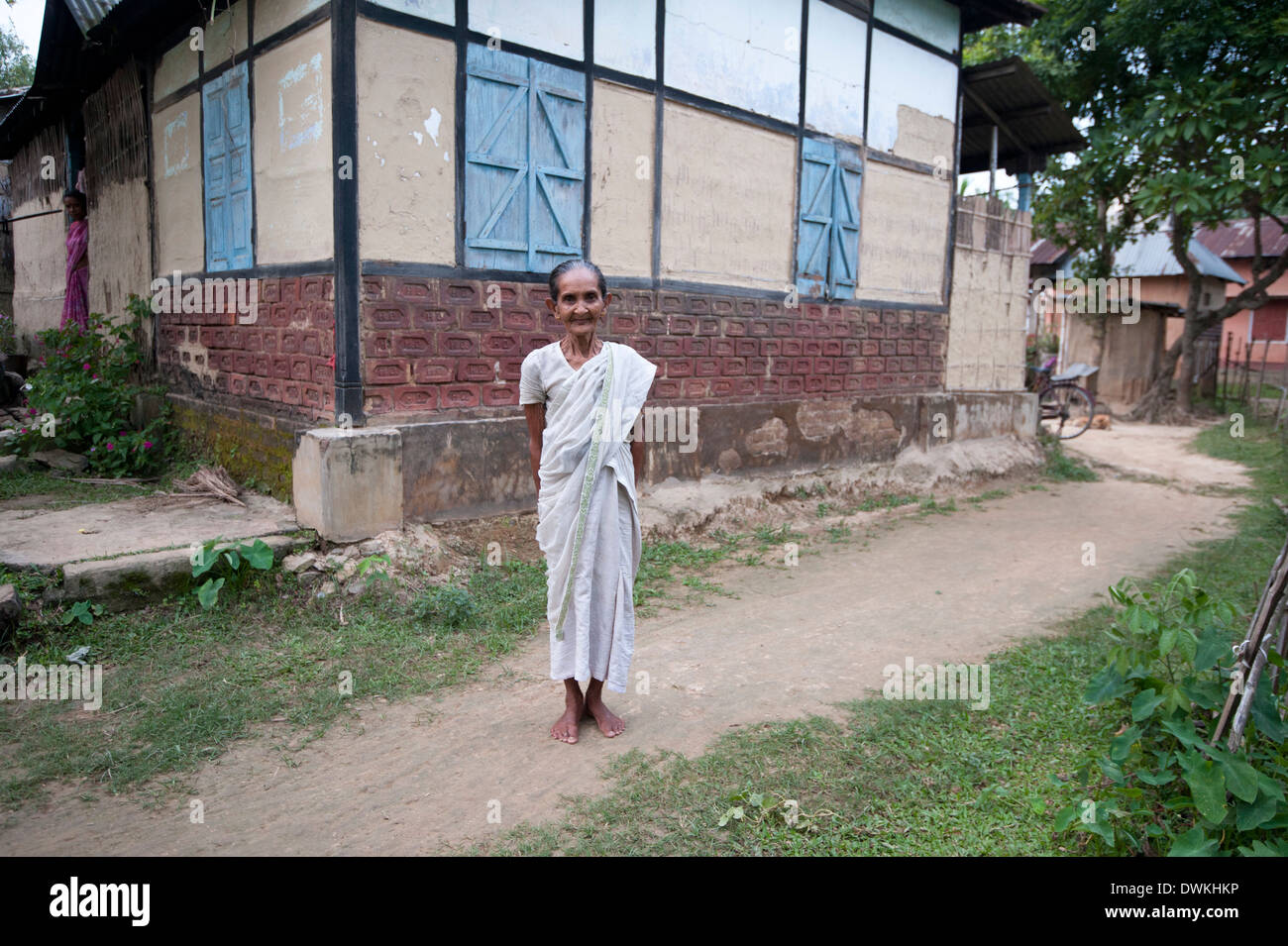 Elderly village woman outside her house wearing white sari denoting her ...